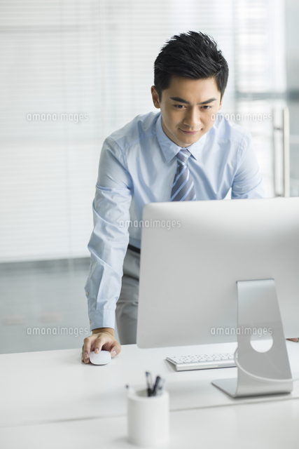 Young businessman using computer in office[11091008468]の写真素材・イラスト素材｜アマナ ...