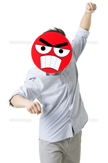 Young man with a angry emoticon face in front of his face[11091010601]の ...