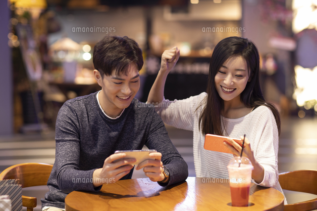 Happy young Chinese couple playing mobile games[11091038063]の写真素材・イラスト ...