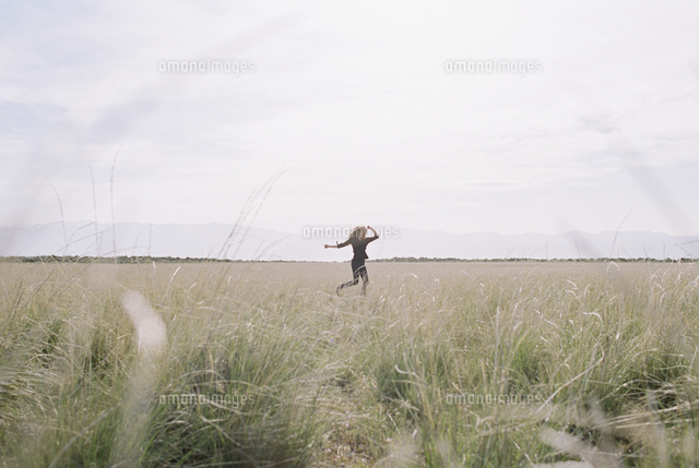 A woman running through long grass, view from a distance.[11093006264]の ...