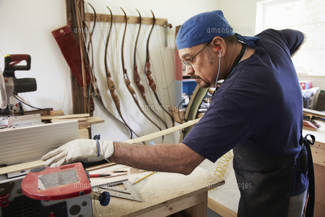 A bow maker working on a wooden bow in his workshop.[11093013571]の写真素材 ...