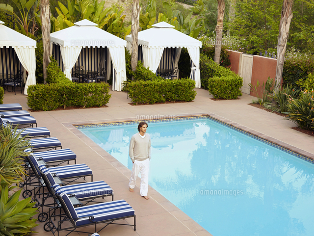 Caucasian man walking at poolside[11093034757]の写真素材・イラスト素材｜アマナイメージズ