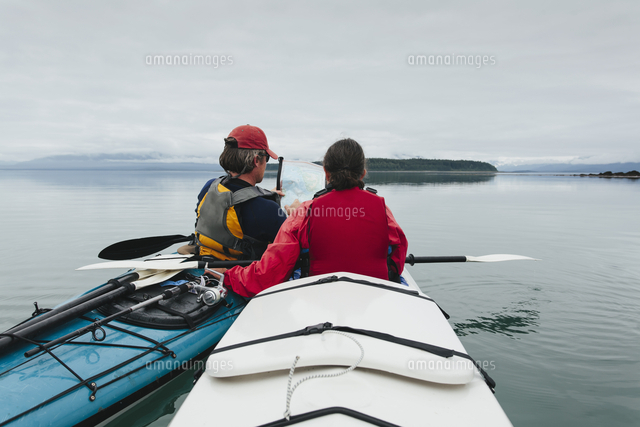 Sea kayakers looking at nautical chart and mapan inlet on the Alaska ...