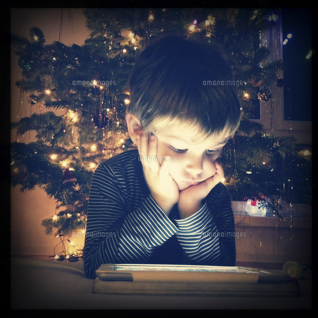 Toddler playing with tablet computer under Christmas tree, Berlin ...