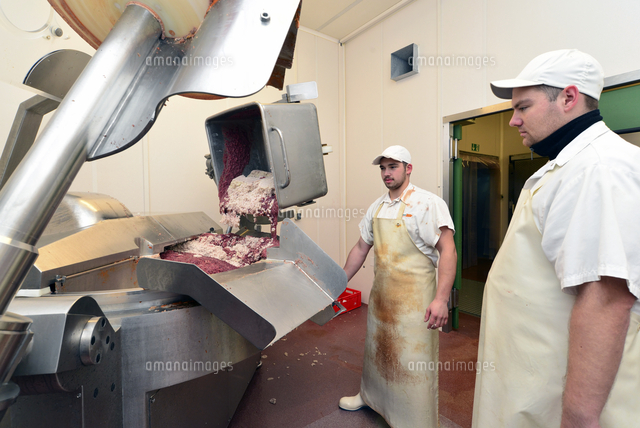 Two men operating and controlling silent cutter in a butcher ...