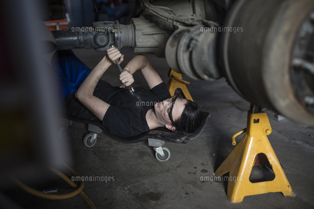 Female mechanic working at fire brigade workshop, lying on c ...