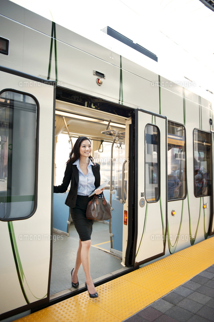 Businesswoman walking off train[11100003781]の写真素材・イラスト素材｜アマナイメージズ