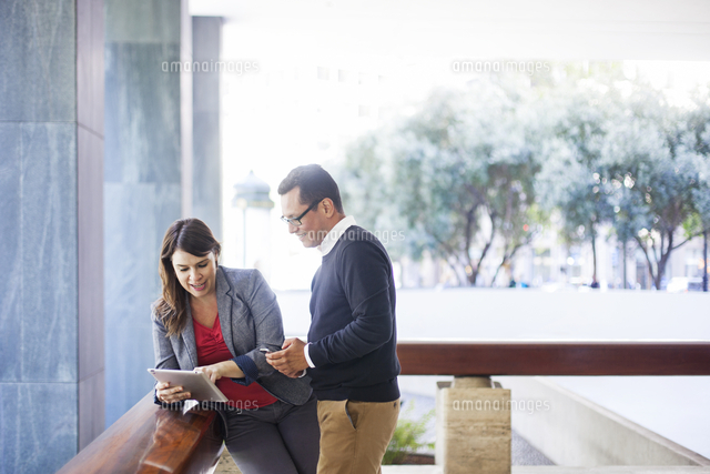 Colleagues using tablet computer while standing in office[11100043915]の ...