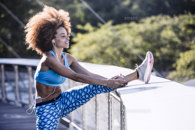 Woman stretching legs while listening music[11100046641]の写真素材・イラスト素材 ...