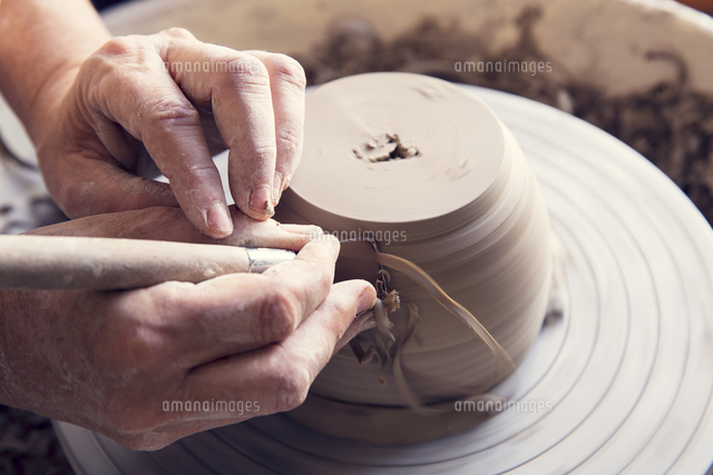 Cropped image of woman molding shape to clay with work tool on pottery ...