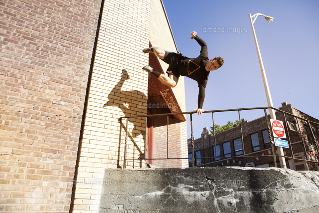 Low angle view of confident man jumping over railing against clear blue ...