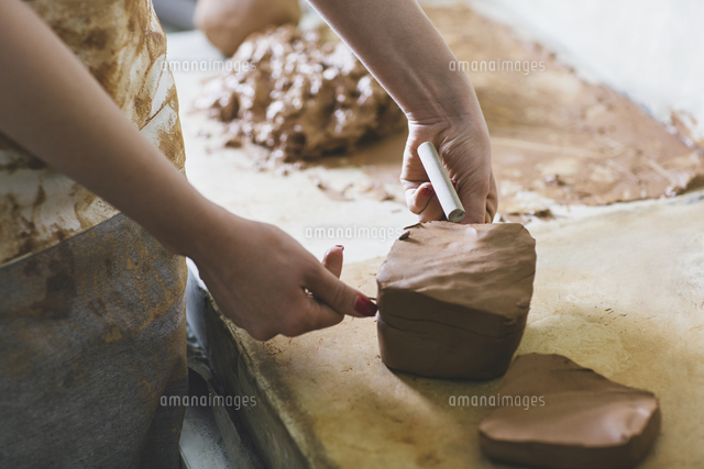 Midsection of female potter making clay on table in workshop ...