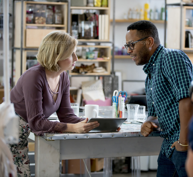 Business people discussing over tablet computer while leaning on table ...