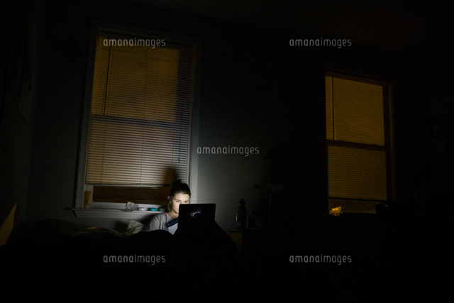 Woman using laptop computer in darkroom at home[11100071042]の写真素材・イラスト ...