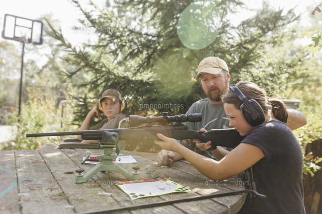 Father and son looking at girl target shooting at backyard[11100078706 ...