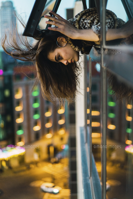 Young woman bending while looking through window[11100079621]の写真素材・イラスト ...