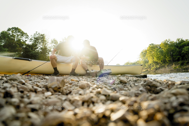 Surface level of friends sitting on boat at lakeshore against clear sky ...