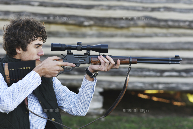 Teenage boy aiming with rifle while standing against wood[11100085064]の ...