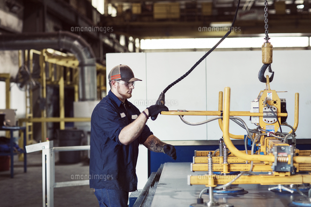 Side view of worker using machinery at industry[11100087134]の写真素材・イラスト ...