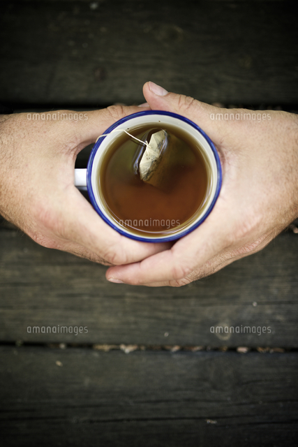 Cropped hands of man holding teabag in cup on wooden table[11100102948 ...