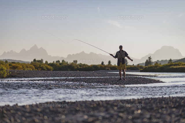 Man holding fishing net while standing at lakeshore against sky during ...