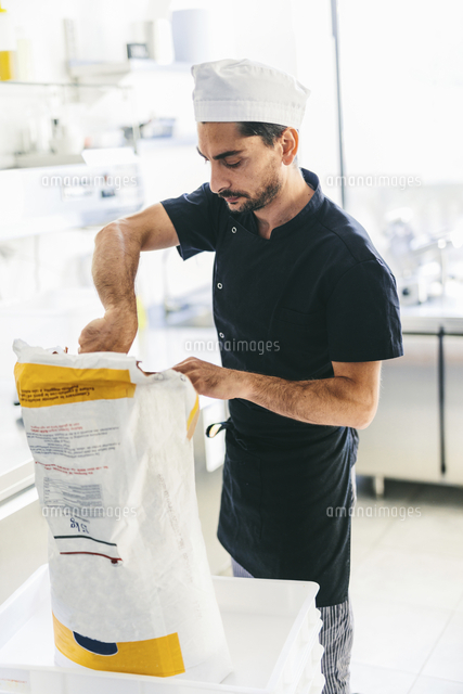 Chef removing flour from packet in commercial kitchen at pizzeria ...