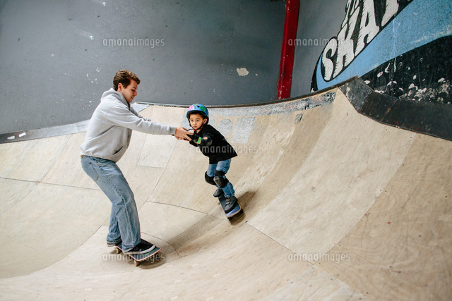 Skateboard instructor holds student's hands while carving[11100119470]の ...