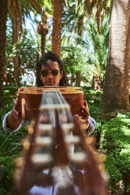 Young musician with classical guitar playing under the shade of some ...