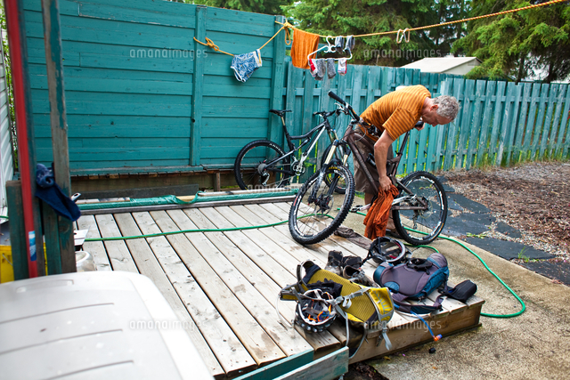 A middle aged man washing down his mountain bike after a muddy ride in ...