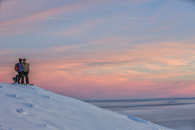 Couple snowshoeing on a mountain in northern Yukon at sunset, Old Crow ...