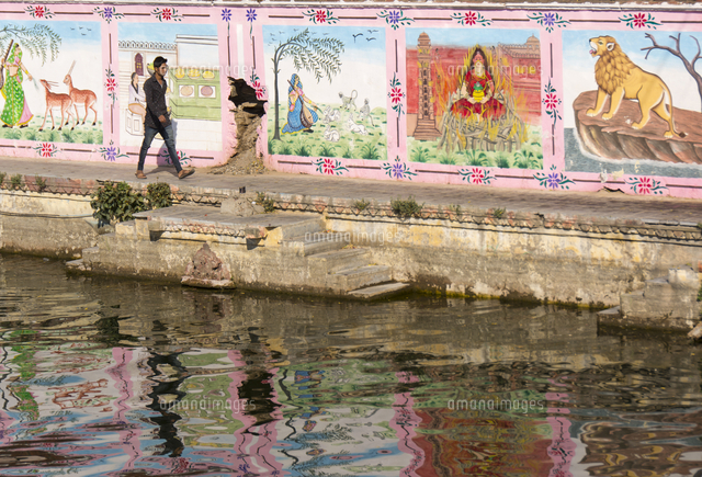 People walk by murals along wall on Lake Pichola, Udaipur, Rajastan ...